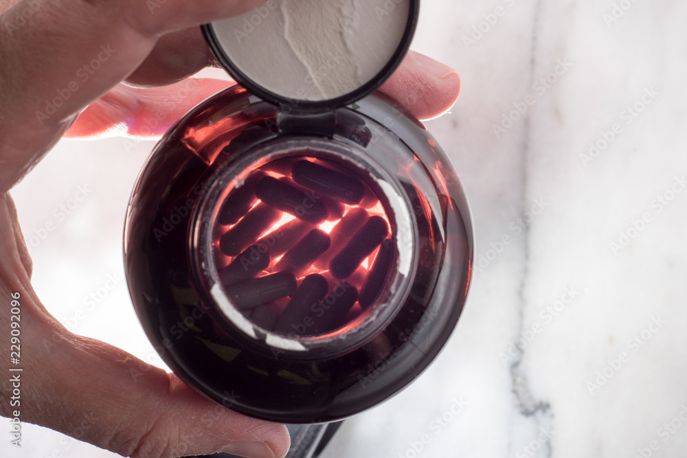 medicine capsules inside bottle with illuminated bottom and clear ...