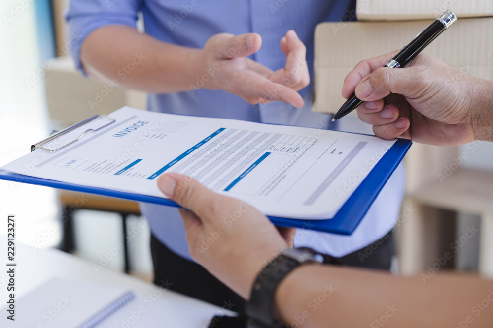 Young man signing invoice bill from delivery man after receiving parcel ...