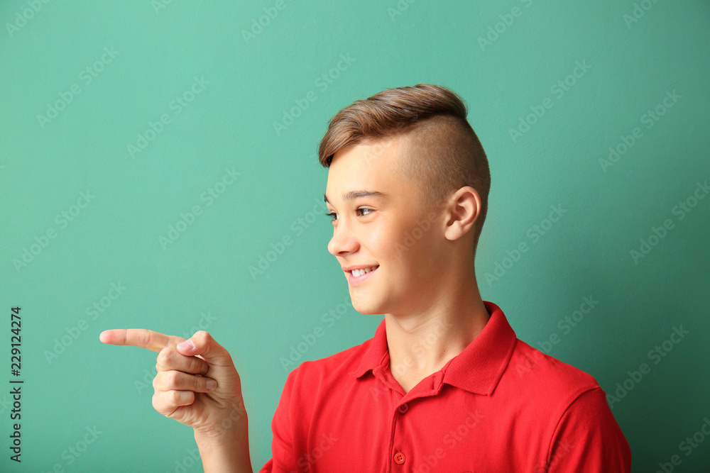 Teenage boy pointing at something on color background Stock Photo ...