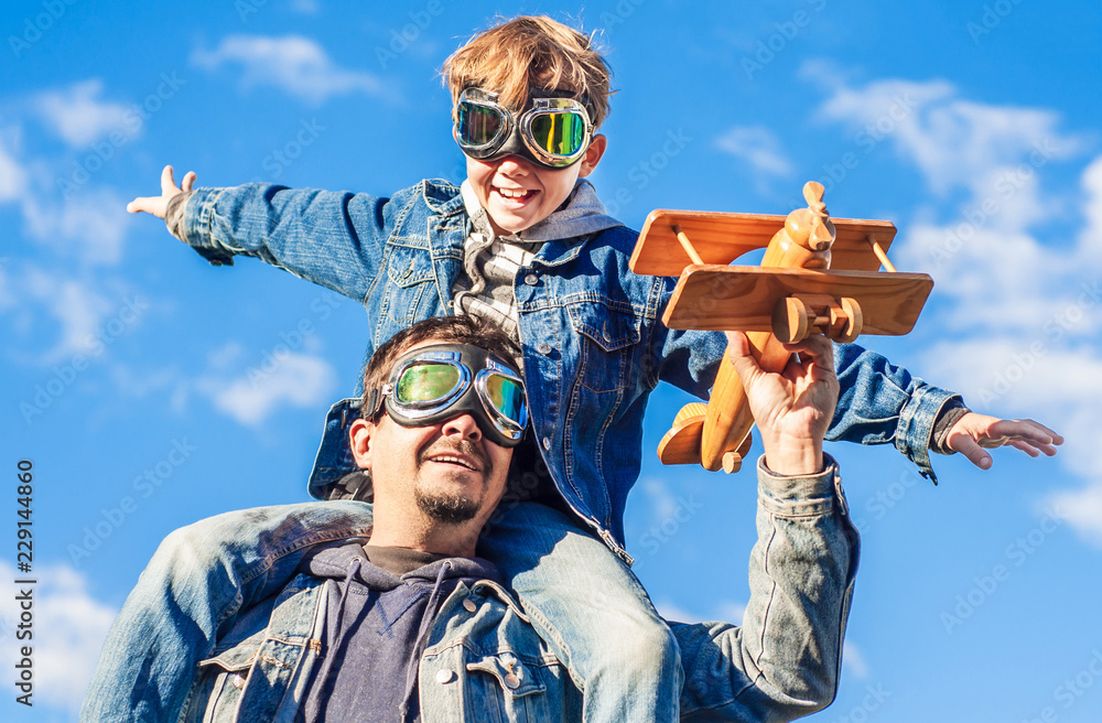 Father and son in jeans clothes and goggles pilots simulate airplane ...