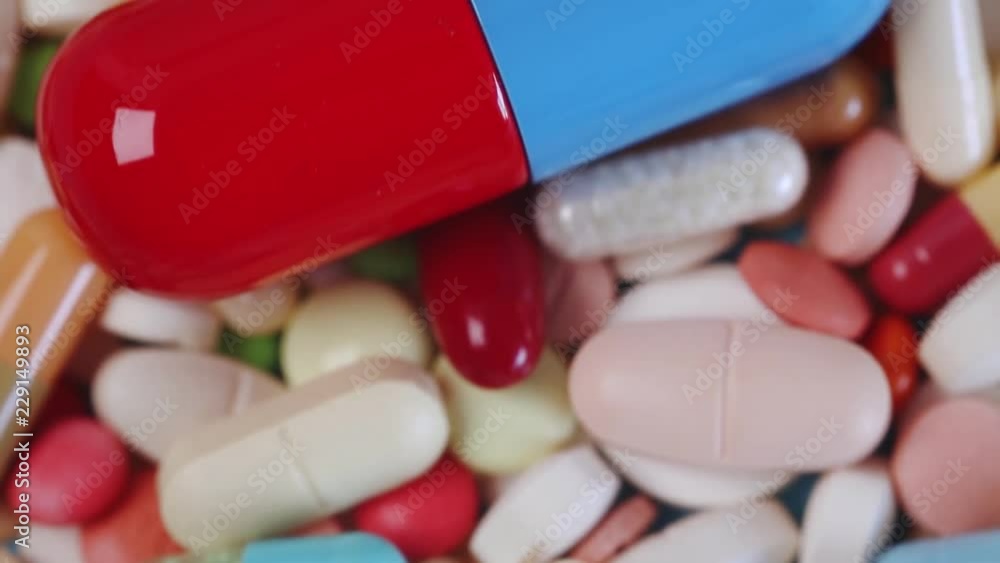 Closeup tilt view of large pill among many colorful pills Stock Video ...
