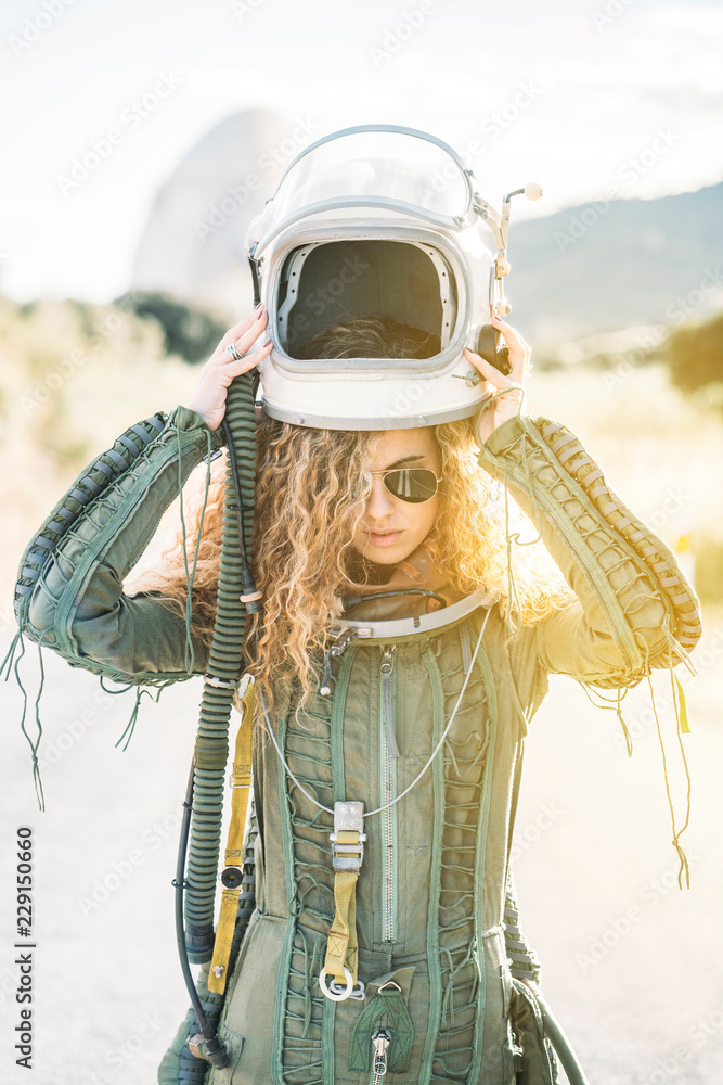 Beautiful woman putting the helmet dressed as an astronaut. Stock Photo ...
