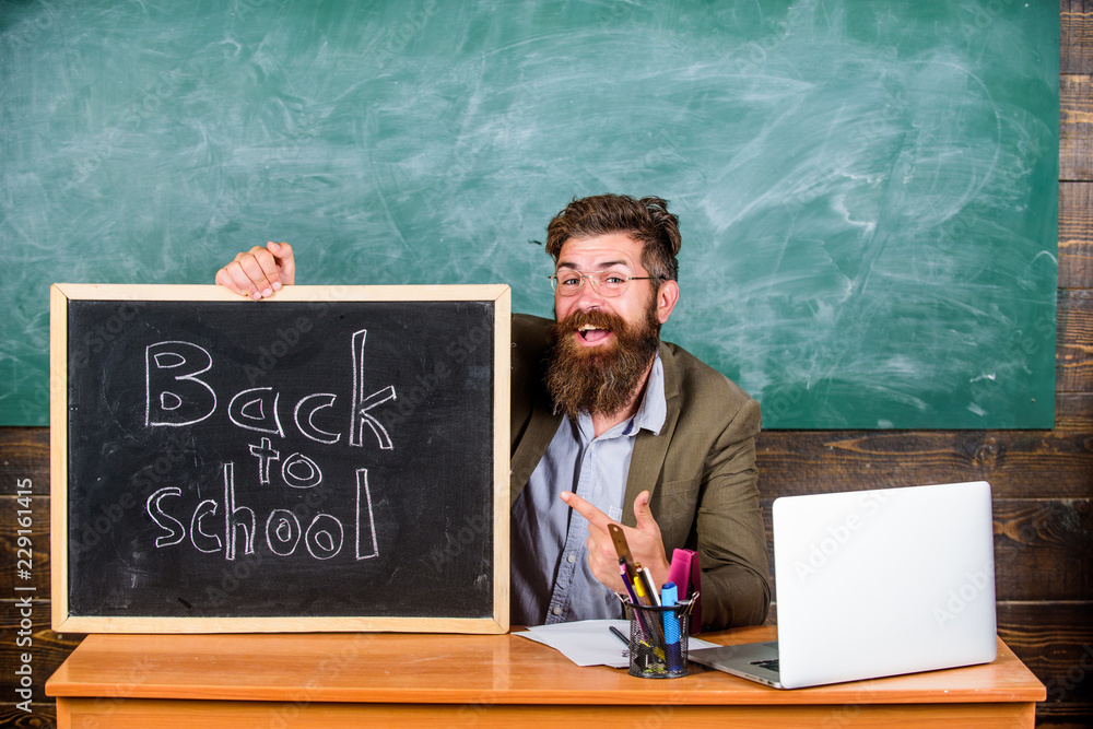 Teacher or school principal welcomes with blackboard inscription back ...
