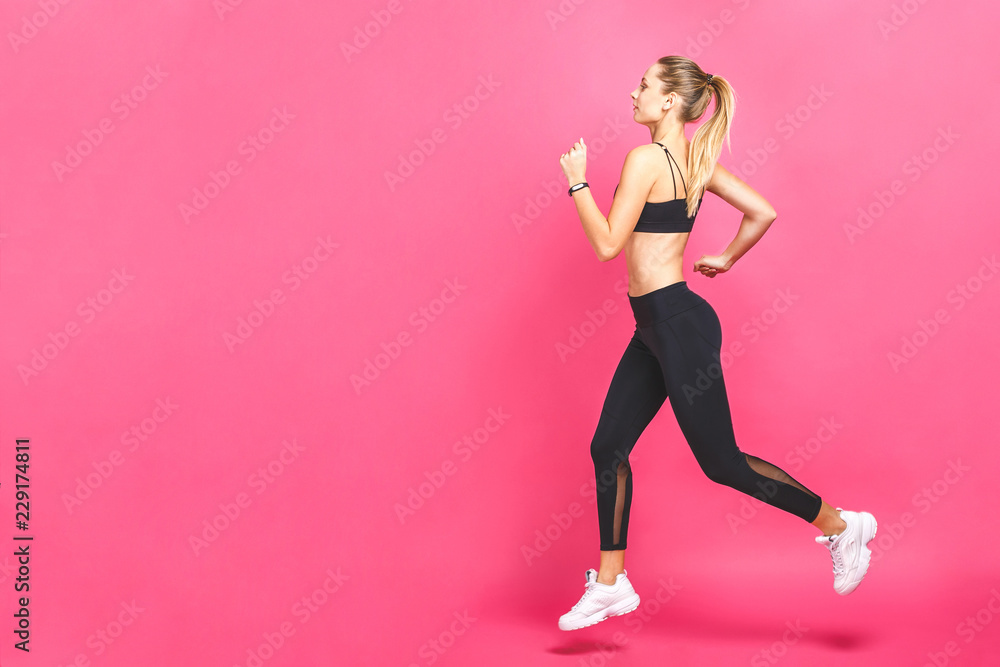 Full length picture of a sports woman running in studio over pink ...