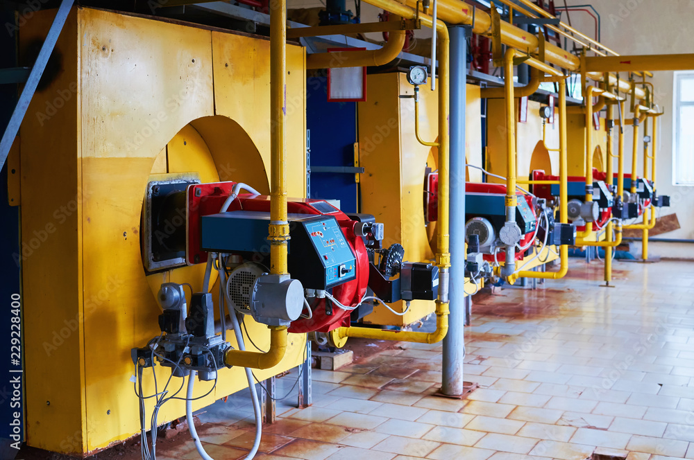 Boiler room with four large yellow cauldrons and red-blue burners ...