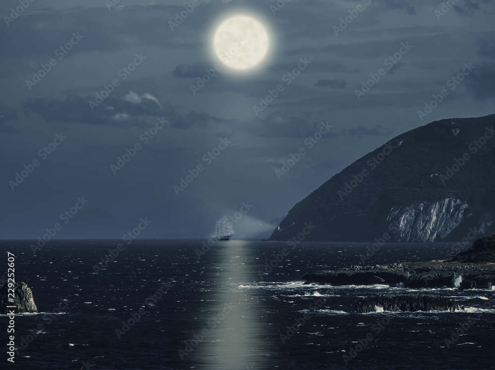 Large lagoon in the ocean under the moon and ship in the beam of the ...