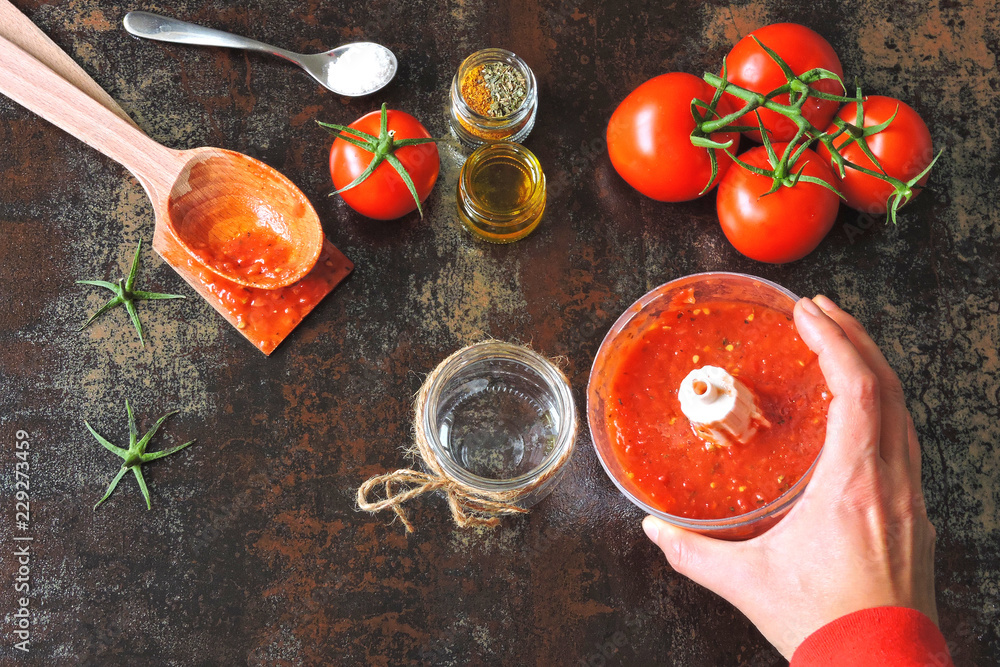 Cooking homemade tomato sauce. Tomatoes and spices. Female hands in red ...