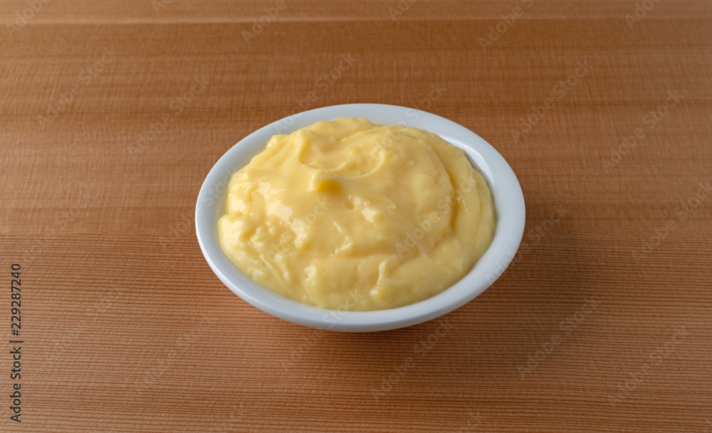 Side view of homemade banana cream pudding in a white dish atop a wood ...