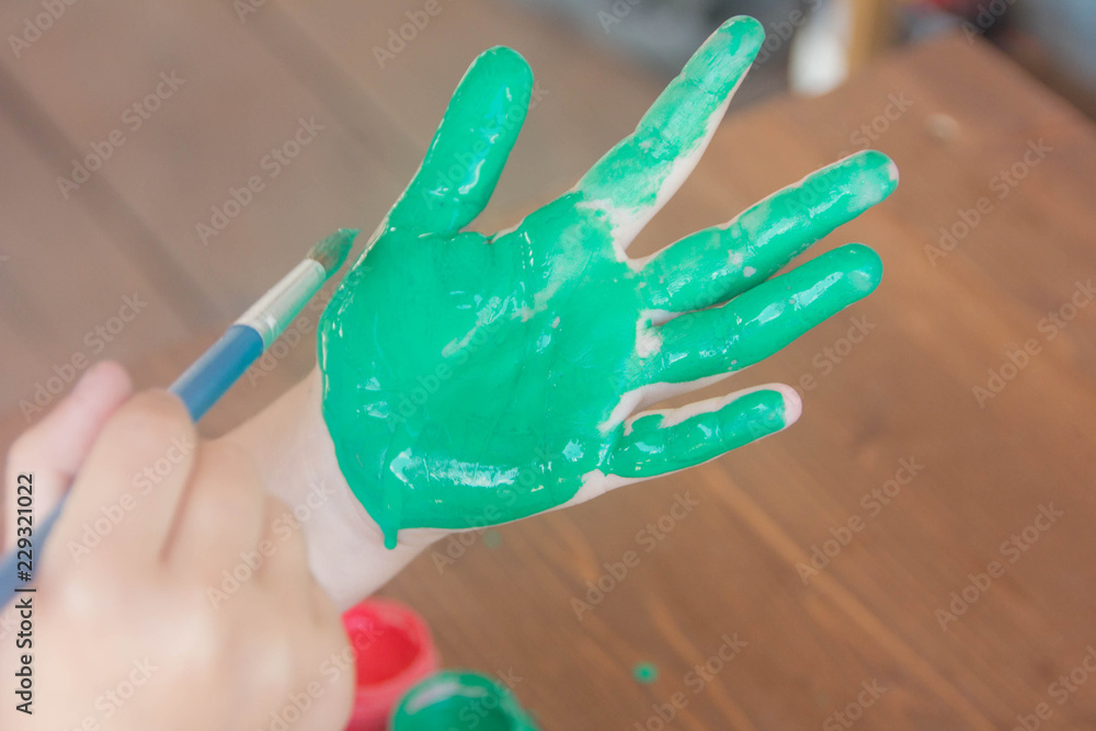 Paint your hand with green paint. A child paints a palm paint, close-up ...