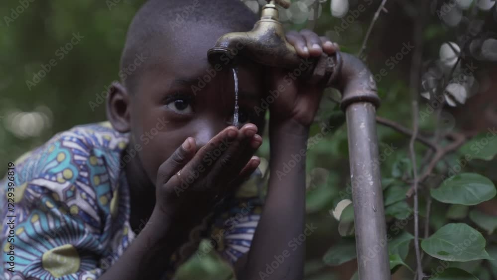 Handsome African boy drinking clean, fresh water from a tap just ...