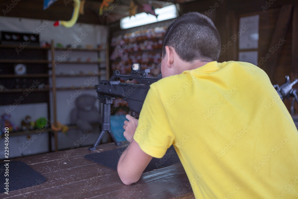 Caucasian teenage boy aiming with black pneumatic rifle in a shooting ...
