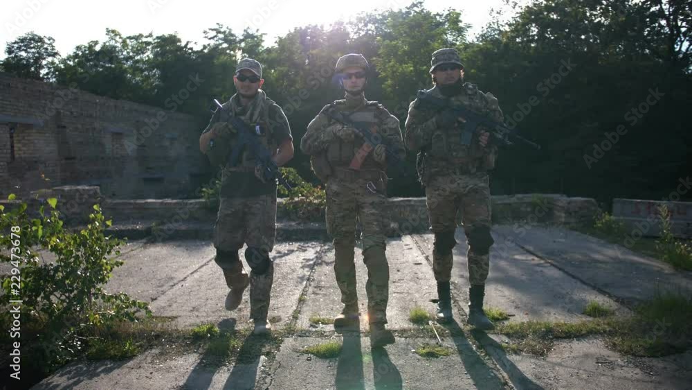 Squad of army soldiers with combat rifles in full ammunition patrolling ...