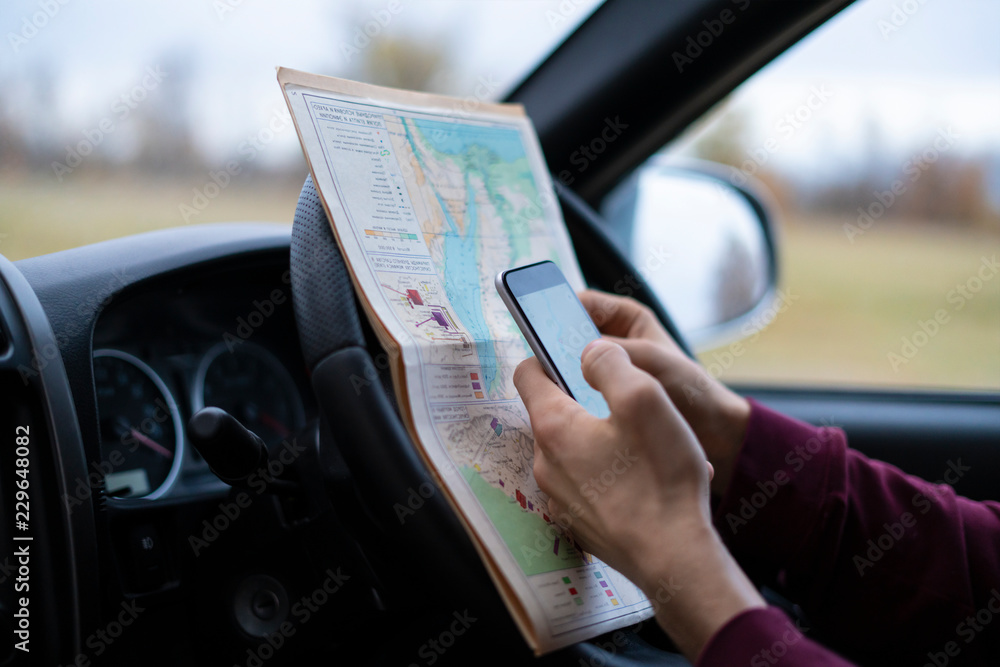 sitting in the car driver hands holding the map and searching the way ...