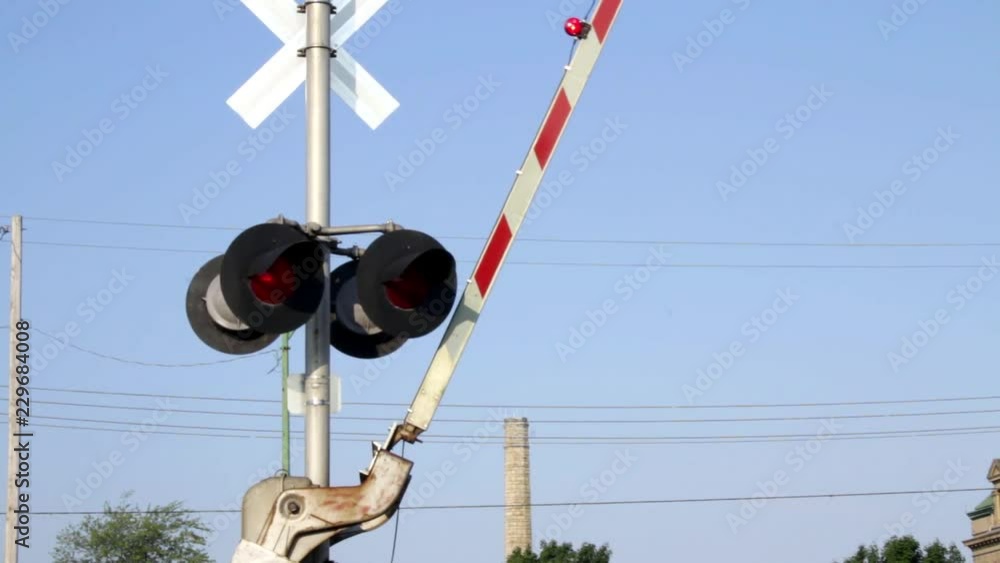 Railroad crossing signal with flashing lights and arm lowering to the ...