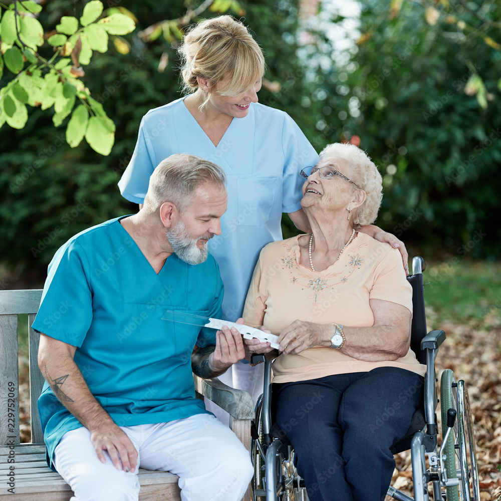 Foto de Pfleger Pflegerin erklären Seniorin die Aufteilung der ...