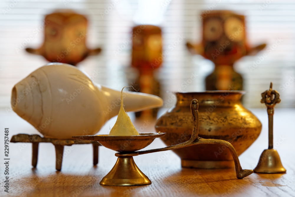 Ghee candle, conch shell with brass bell and water pot, the blurry ...
