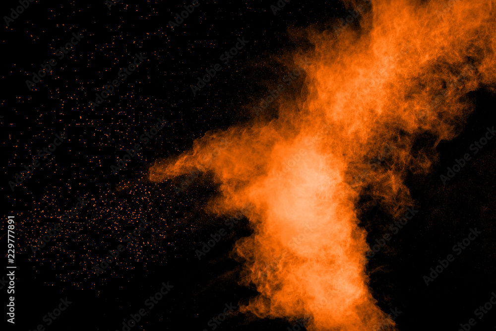 Abstract orange powder explosion on black background. Freeze motion of ...