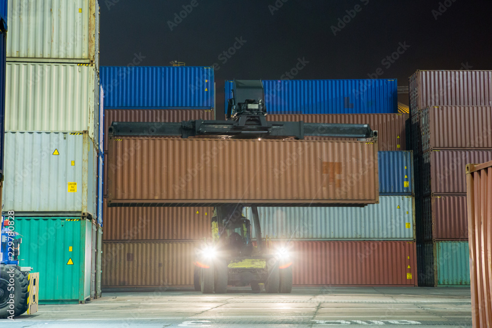 Loading and unloading containers in port on night. Reach stacker is ...