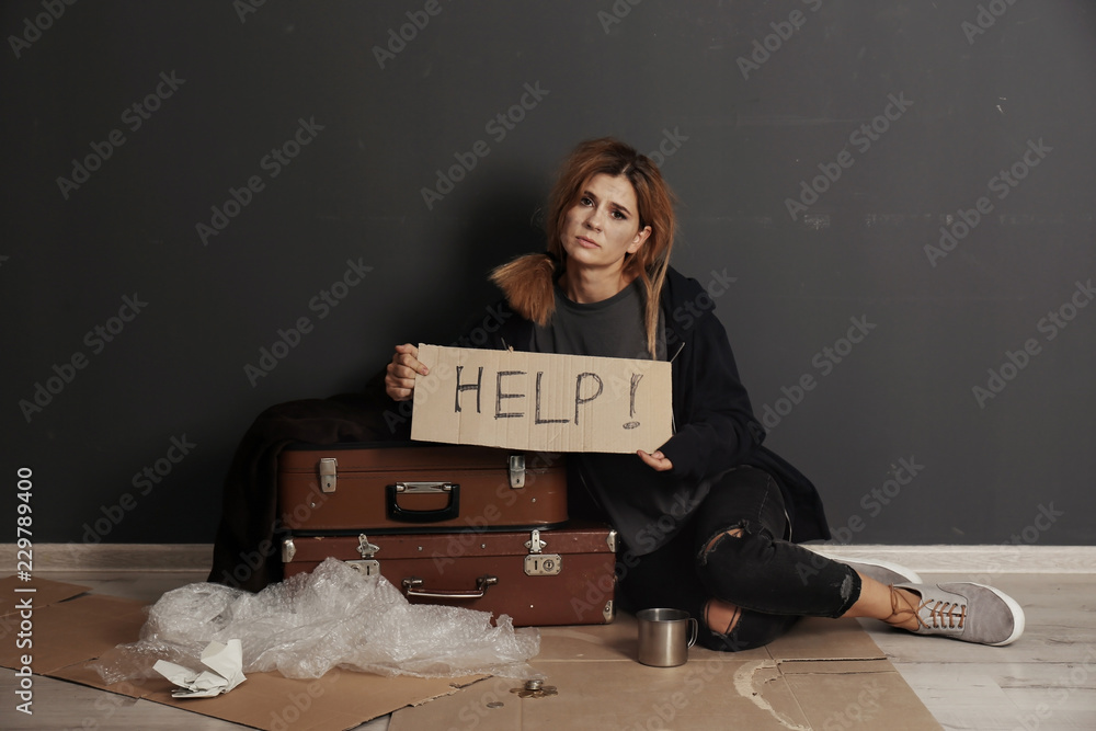 Poor homeless woman asking for help on floor near dark wall Stock Photo ...