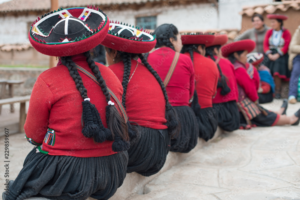 Quechua women sitting in a line with their traditional dress and ...
