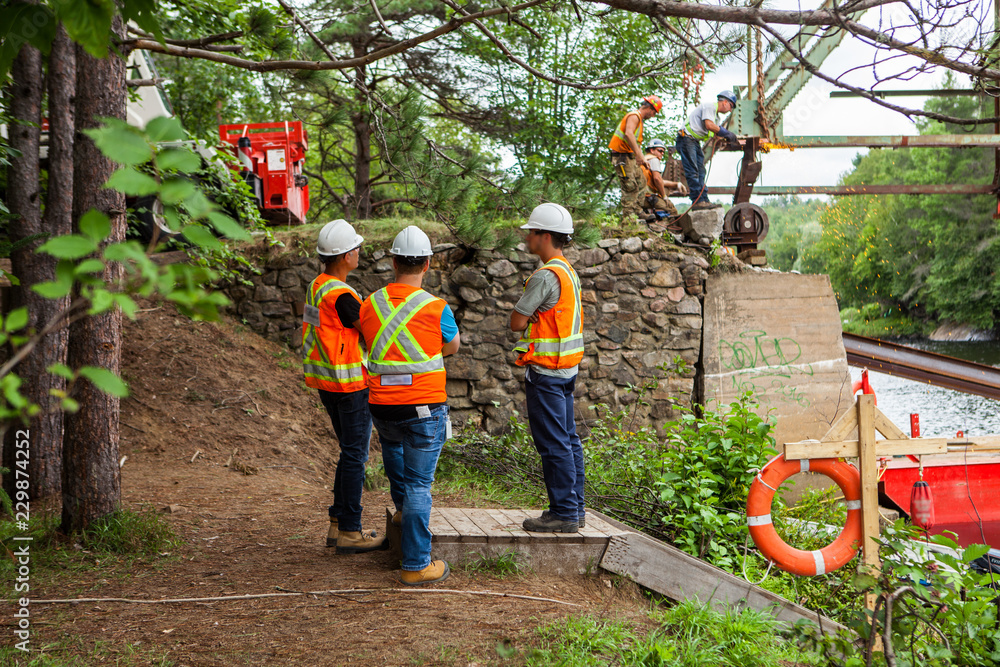 Six men on a construction site working on a bridge. Each of them ...