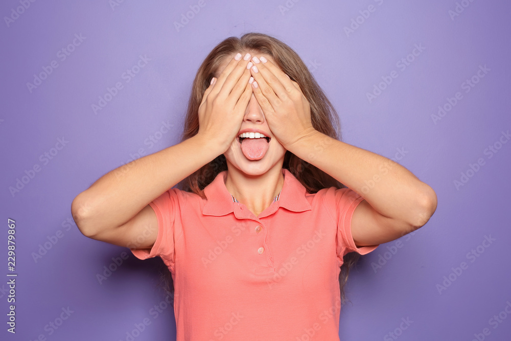 Portrait of funny young woman covering eyes with her hands on color ...