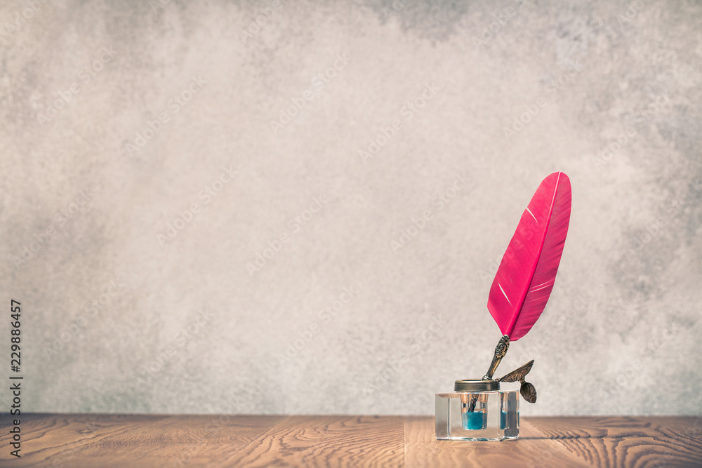 Red quill ink pen with inkwell on wooden desk front concrete wall ...