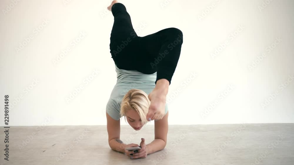 Vidéo Stock Model size plus do yoga handstand twine pose and use phone ...