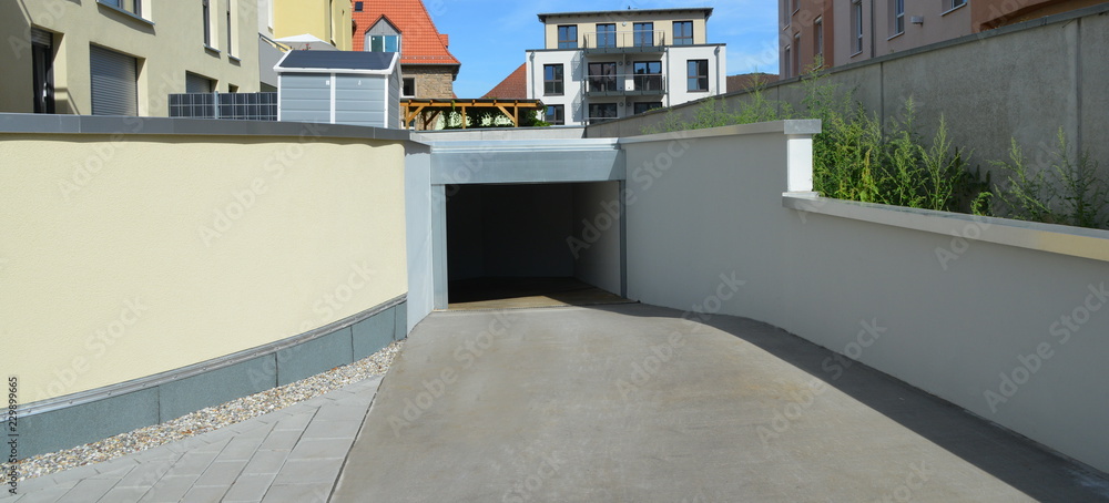 Moderne Tiefgaragen-Zufahrt mit Automatik-Tor. Einfahrt mit Beton ...