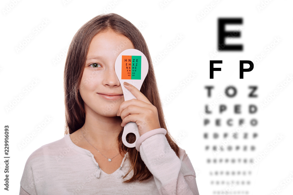 Teenage girl having eye exam with one eye covering using special tool ...