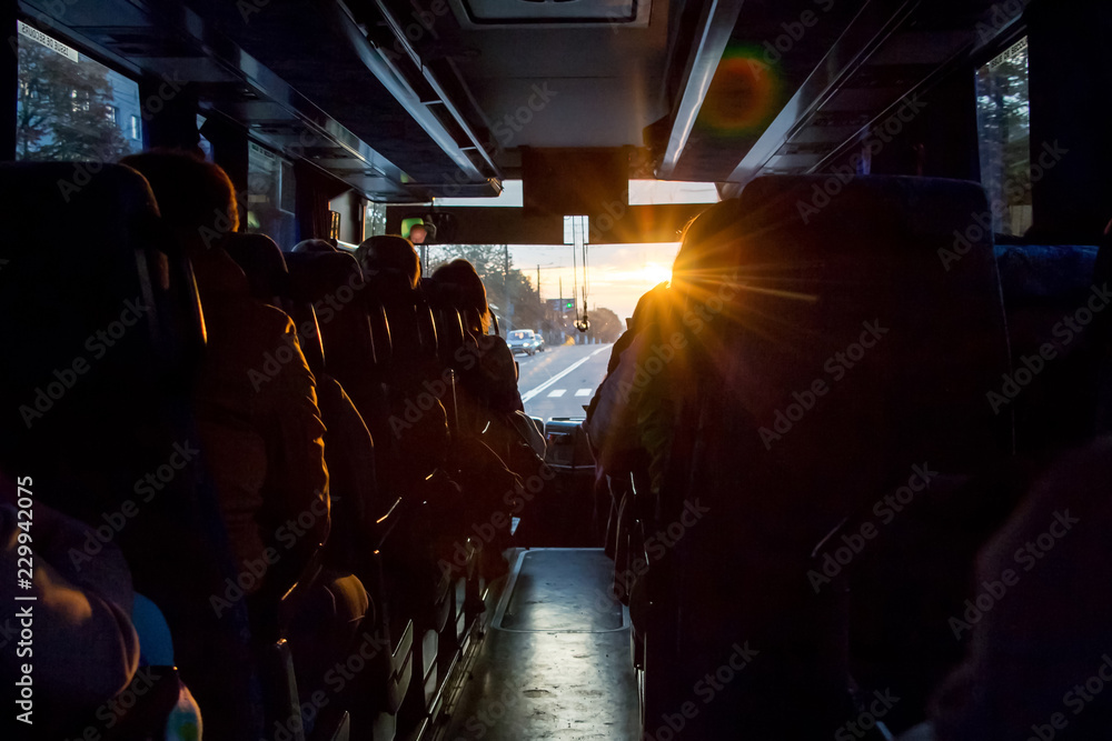 Saloon of bus with passengers. The light of the sun penetrates through ...