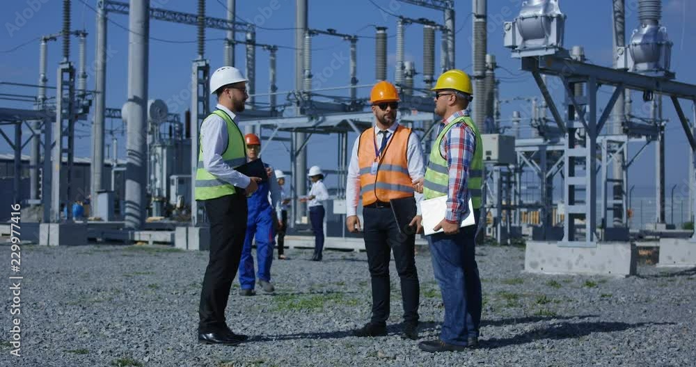 Group of adult diverse men in hardhats gathering on transformer ...