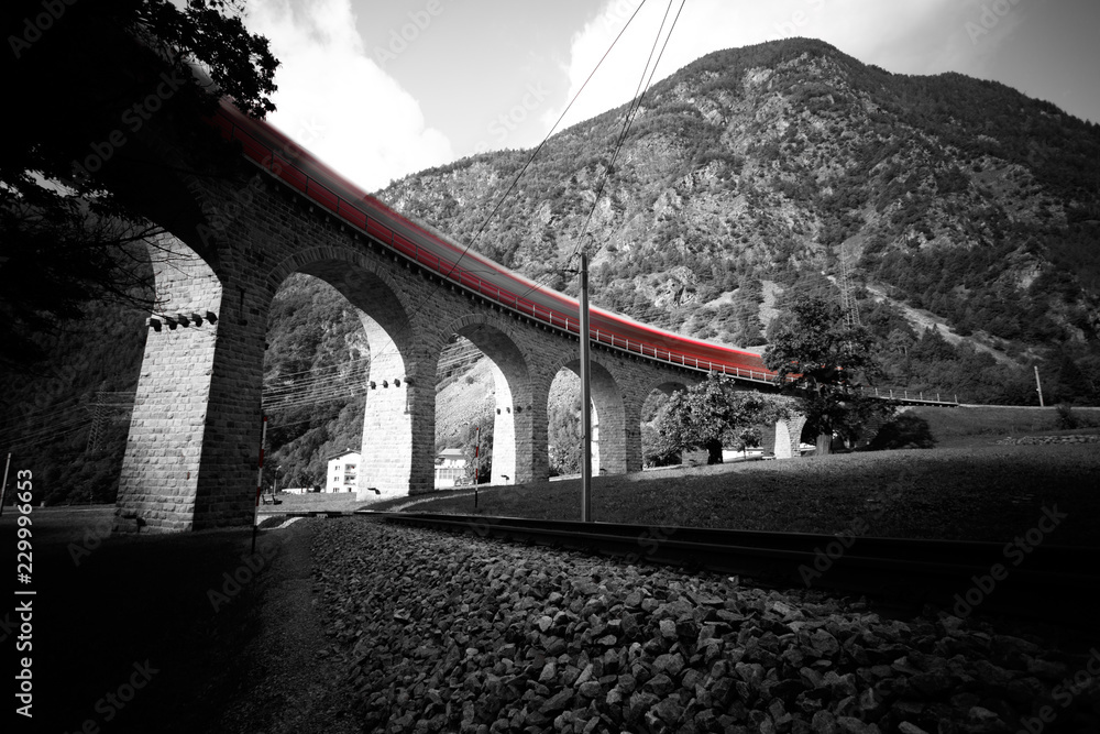 Train passing over the Brusio Spiral Viaduct in UNESCO landscape along ...