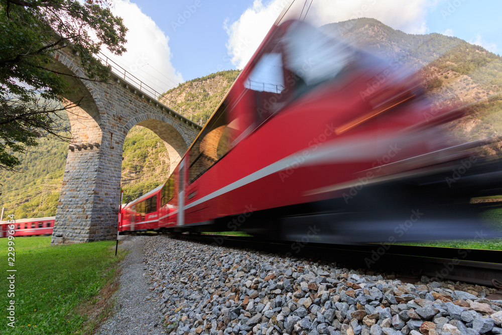 Train passing under the Brusio Spiral Viaduct in UNESCO landscape along ...