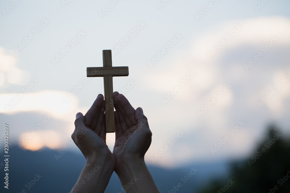 Woman hands holding holy lift of christian cross with light sunset ...
