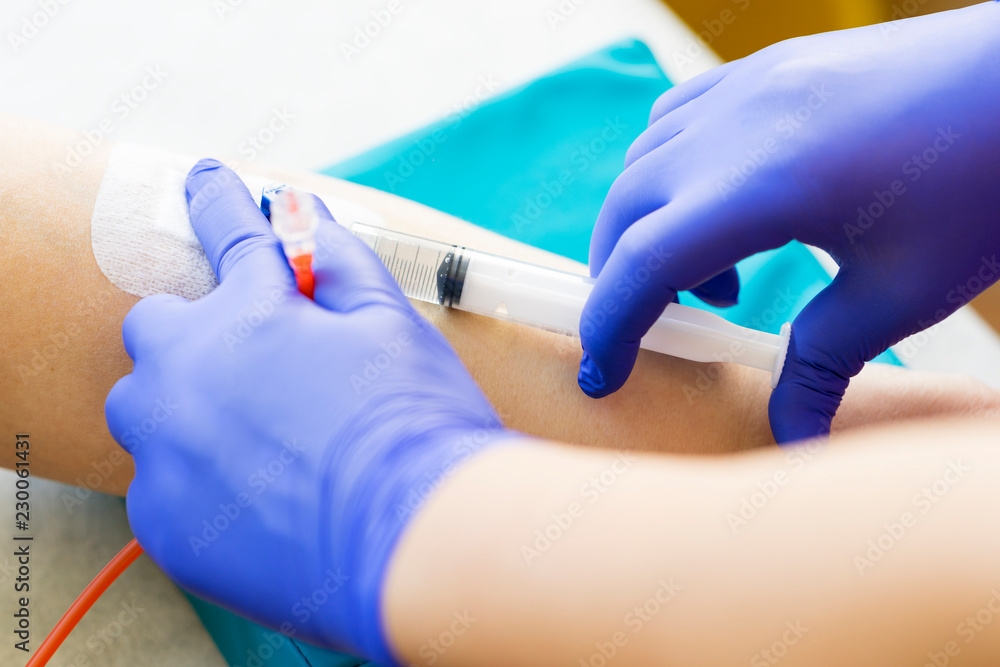 medical nurse with blue latex gloves inputs liquid medicine by syringe ...