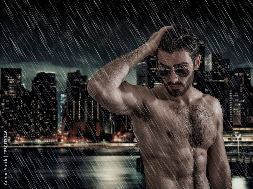 Handsome shirtless young man outdoor at night under pouring rain, with ...