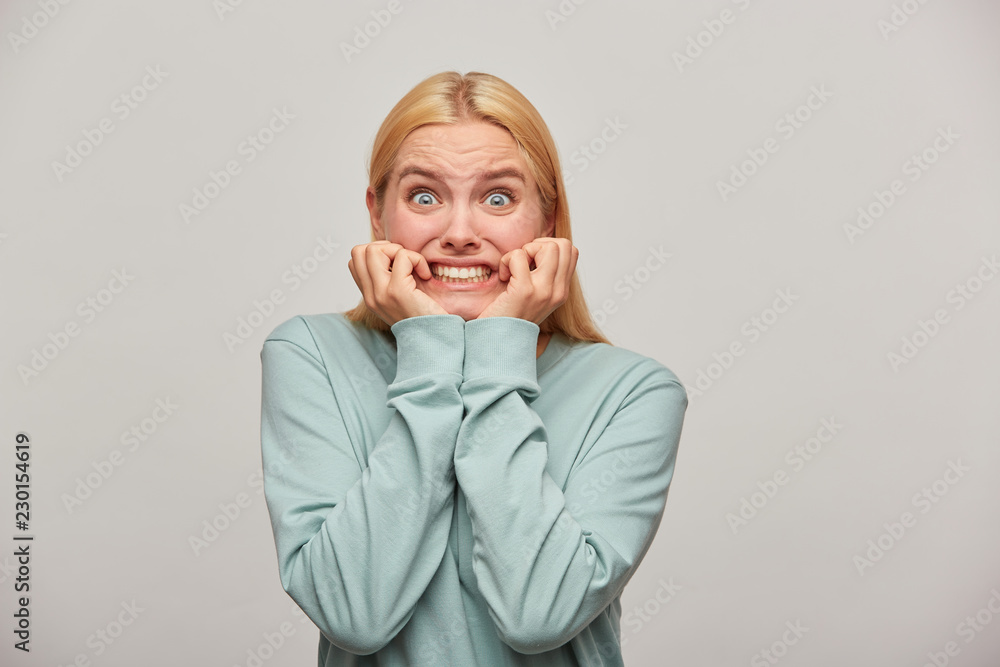 Scared blonde girl looks frightened afraid chattering teeth with fear ...