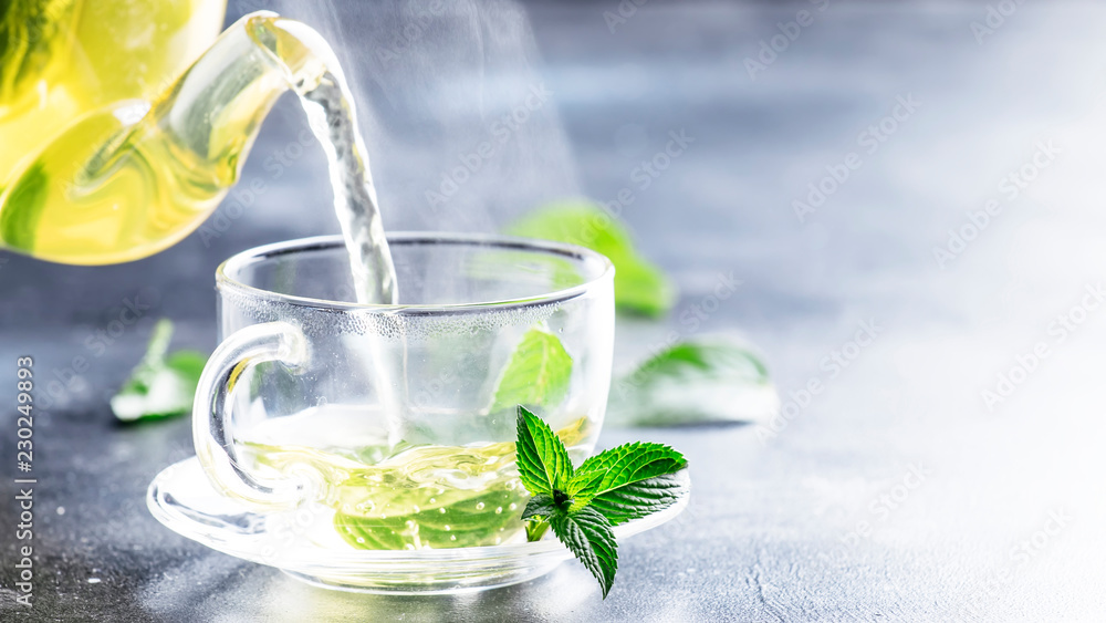 Hot chinese green tea with mint, with splash pouring from the kettle ...