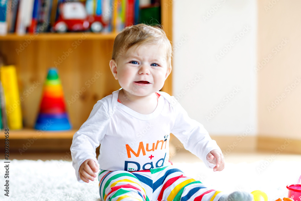 Crying sad baby girl playing with educational toys in nursery. hysteric ...