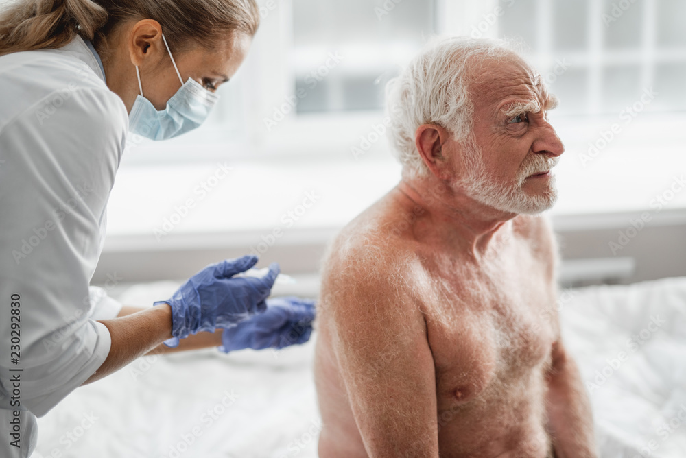 Side view portrait of doctor in sterile gloves giving shot to patient ...
