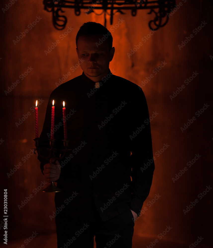 Young Catholic Praying priest. Portrait of priest Next to the candles ...