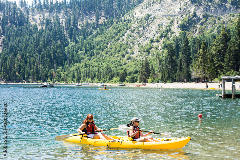 Two female friends row in a dual kayak on Lake Tahoe in Emerald Bay ...