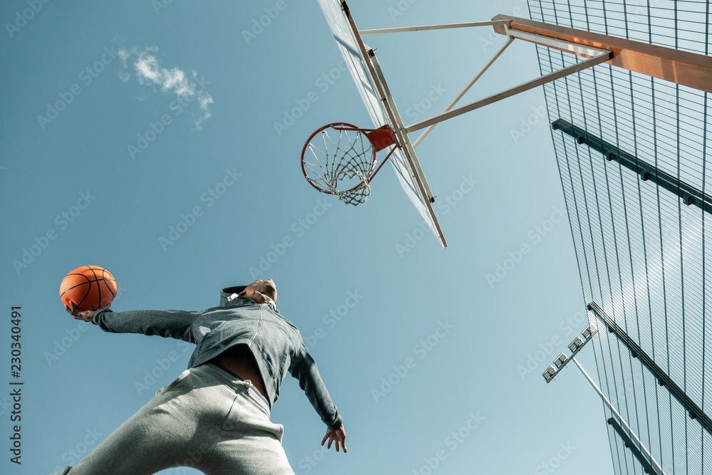 Winning throw. Low angle of a basketball player jumping while doing the ...