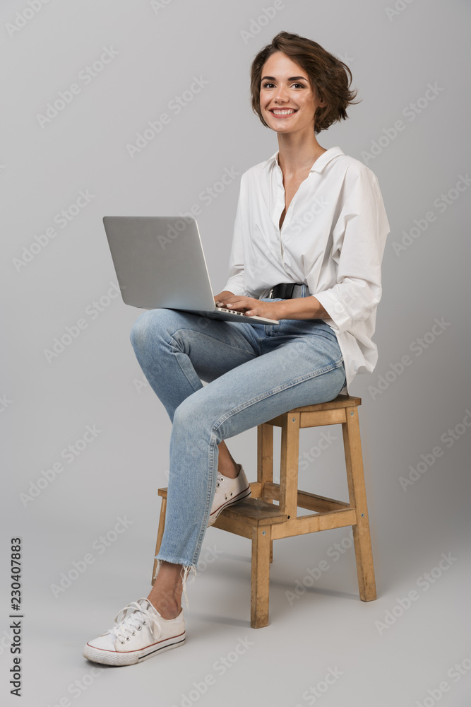 Young business woman posing isolated over grey wall background sitting ...