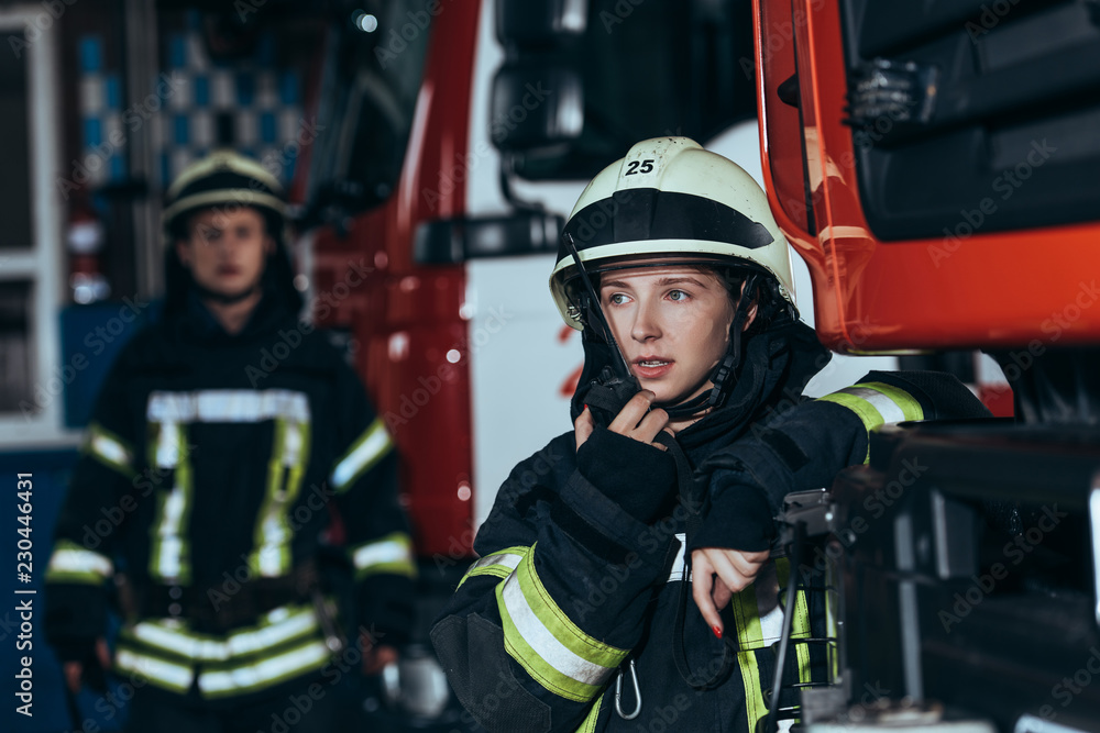 selective focus of female firefighter talking on portable radio set ...