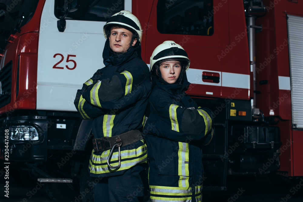 portrait of firefighters in fireproof uniform and helmets with arms ...