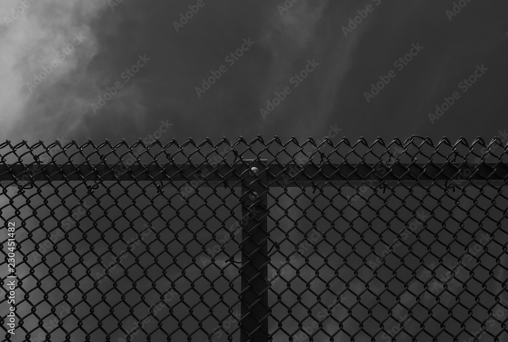 Isolated black and white chain link fence. Moody cloud background ...