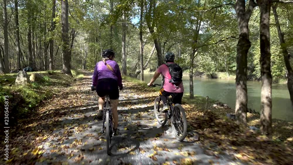 Mother and teenage son biking side by side on a rural gravel road with ...