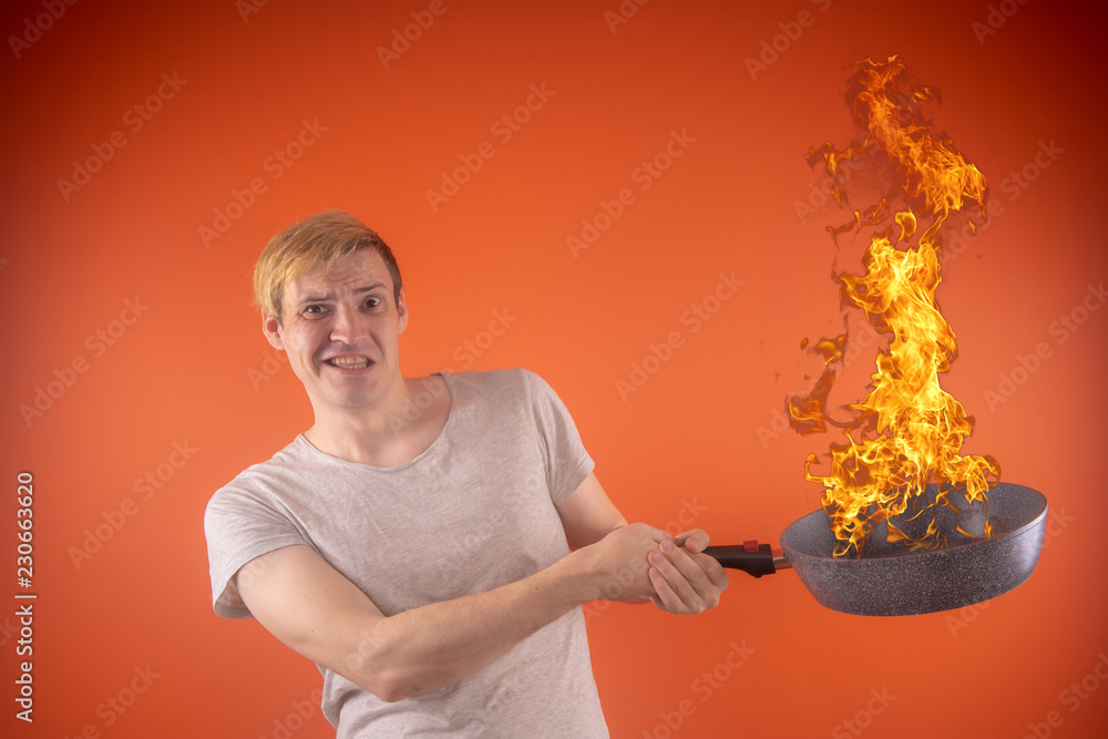 Emotional guy holding a frying pan in his hands, on an orange ...